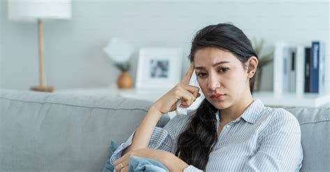 아시아의 아름다운 불행한 여자는 소파에 앉아 좌절하고 스트레스를 느낀다 불안 우울증 속상함 및 슬픔을 느끼는 심리적 문제가 있는 매력적인 걱정 여성은 집에서 건강을 위해