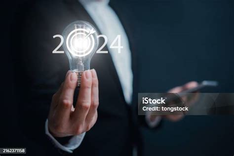 2024년 새해 복 많이 받으세요 사업가 2024년에 아이디어와 목표를 보여주세요 2024년 전구를 들고 있는 사업가 계획 기회 목표 사고방식 비즈니스 전략 12월에 대한