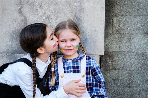 얼굴에 러시아와 우크라이나 어 국기와 포옹하고 키스하는 두 어린 소녀의 초상화 평화의 개념 증오하는 사람들에 대한 아이들의 전쟁과 우정을 중지 6 7 살에 대한 스톡 사진