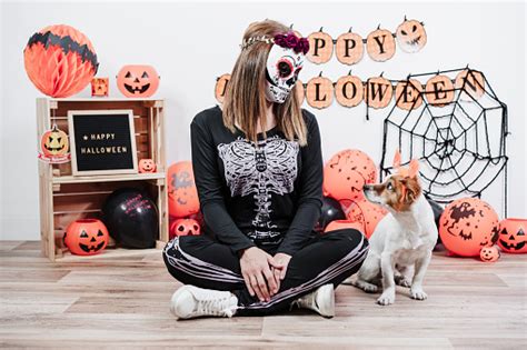 재미있는 유령 의상과 할로윈 축하 기간 동안 멕시코 얼굴 마스크를 착용 하는 여자와 잭 러셀 개 스켈레톤 의상과 빨간 장미 디아뎀을 머리에 쓰고 있는 여성 할로윈 파티 컨셉