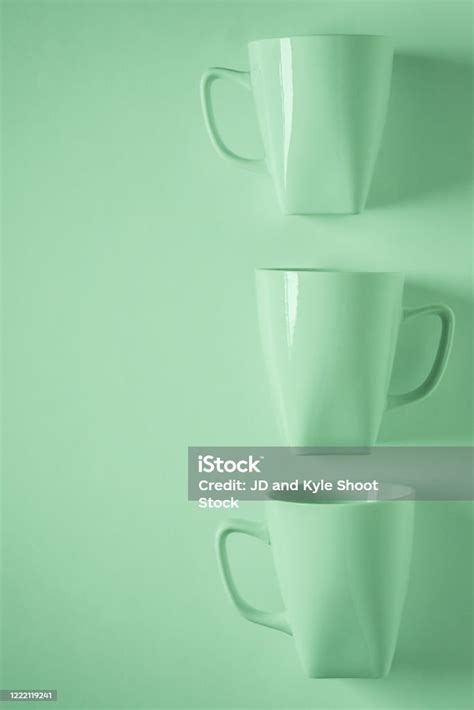 텍스트 복사 또는 복사 공간을 위한 빈 빈 공간과 녹색 배경에 줄지어 있는 3개의 단색 녹색 커피 머그잔 견고한 배경을 가진 세 컵의 현대적인 탑 뷰 컨셉 0명에 대한 스톡
