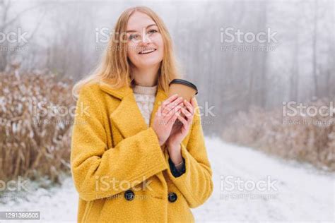 행복한 젊은 여자는 자연 배경 2021 년 의 트렌디 한 색상 위에 종이 커피 컵을 보유하고 노란색 조명 가져 가거나 배달 개념을 가져 가라 공간을 복사합니다 가리기에 대한