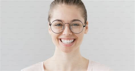 회색 배경에 고립된 젊은 아름다운 여성의 실내 초상화는 현재 상황에 대한 완전한 내용 만족 행복을 표현하는 큰 둥근 안경