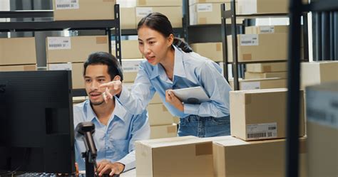 มีความสุขชายเอเชียและผู้หญิงหุ้นส่วนสวมเสื้ออย่างเป็นทางการนั่งอยู่หน้าโต๊ะคอมพิวเตอร ภาพสต็อก