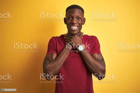 고립 된 노란색 배경 위에 서있는 빨간 티셔츠를 입은 젊은 아프리카 계 미국인 남성이 고통스러운 목졸림 때문에 외치고 질식합니다 건강 문제 질식 과 자살 개념 T 셔츠에