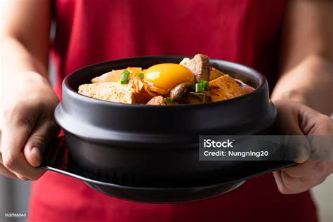 두부 돼지고기 신선한 달걀 노른자를 손으로 들고 있는 한국 돌솥에 넣은 김치국 인간 손에 대한 스톡 사진 및 기타 이미지 인간 손 클로즈업 한국 음식 Istock