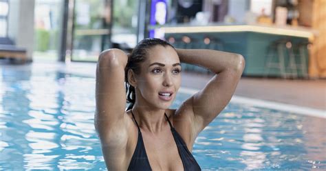 비키니 마른 수영장 가장자리 웃는 관능적 인 모습 카메라에 섹시 한 젊은 검게 그을린 여자의 클로즈업 샷 검은 수영복을 입은 매력적인 여성 모델이 호텔의 수영장 옆