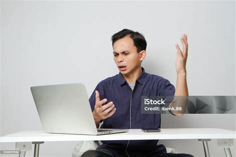 Angry Mad Asian Man In Workplace While Sitting In Front Of Laptop