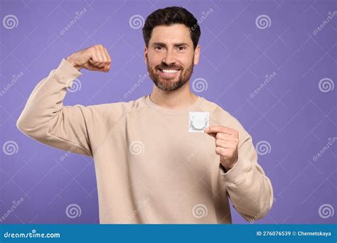 Happy Man Holding Condom On Purple Background Safe Sex Stock Image