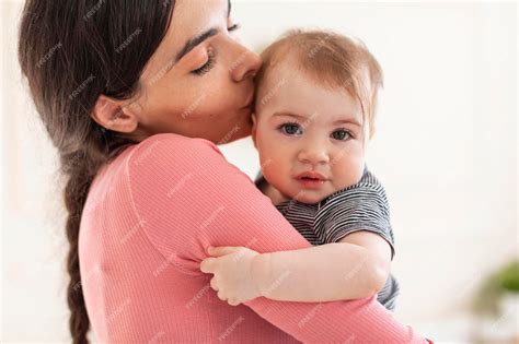 Uma Jovem Mãe Carinhosa Segurando E Beijando Uma Doce Menininha Mãe E