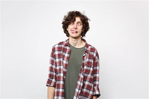 비스듬한 눈과 스튜디오에서 흰색 벽 배경에 고립 된 혀를 보여주는 캐주얼 복장에 미친로 니 젊은 남자의 초상화 사람들은 진심으로 감정 라이프 스타일 개념입니다 복사 공간을