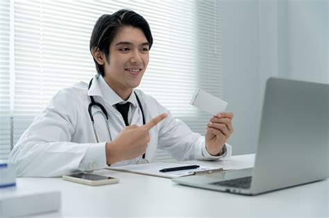 원격 의료 의사는 화상 회의를 통해 환자에게 약을 설명합니다 아시아 의사는 질병을 설명하면서 통신을 통해 환자를 치료하고 있습니다 건강을 위한 기술 25 29세에 대한 스톡