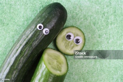 얼룩덜룩 한 녹색 배경에 야채 어린이 건강 식생활 유머러스 한 개념 복사 공간을 가진 전체 오이와 오이 조각으로 만든 재미 있고 만화 캐릭터의 클로즈업 이미지 오이에 대한