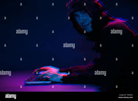 Hacker In The Hood Working With Computer Typing Text In Dark Room Image With Glitch Effect