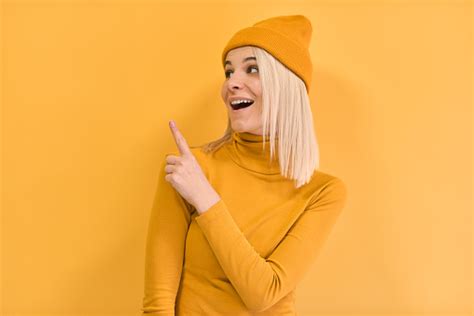 행복 한 백인 여자 금발 머리의 가로 스튜디오 초상화와 함께 나타냅니다 빈 복사본 공간 광고 또는 프로 모션 텍스트 노란 배경에 포즈 쇼 장소에서 앞 손가락 가리키기에 대한