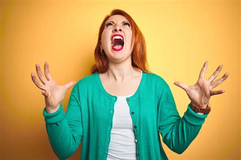 Youg 아름다운 빨간 머리 여자 고립 된 노란색 배경 에 겨울 녹색 스웨터를 입고 미친 미친 소리와 공격적인 표정과 팔을 제기 고함 좌절 개념입니다 감정에 대한 스톡 사진