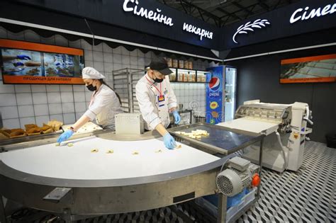 Two Man And Woman Bakers Making Sweet Rolls Using An Automatic Bakery Production Line And Dough