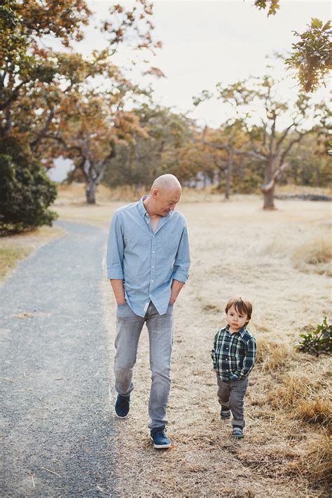 Asian Dad Spending Time With Son Outside Walking In Nature By Stocksy