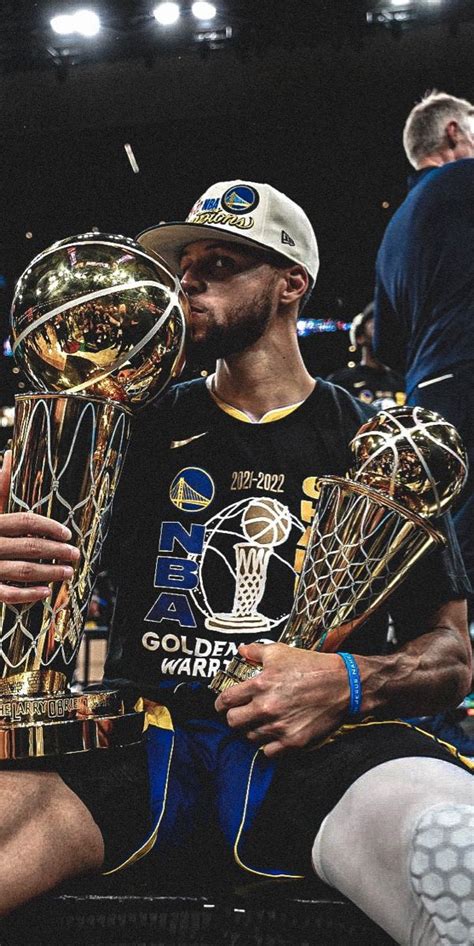 A Man Holding Two Basketball Trophies In His Hands
