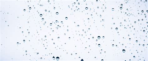 흰색 유리에 빗방울이 있는 최소한의 조명 배경 비오는 물방울이 있는 가벼운 젖은 창문이 푸른 빛으로 근접 촬영됩니다 빗방울이