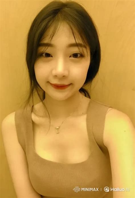 아늑한 방 안 따뜻한 조명이 은은하게 비추는 공간에서 한국인 여자친구가 갈색 나시티를 입고 셀카를 찍고 있다 여자친구는