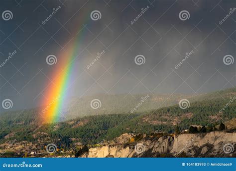 Vibrant Rainbow Shining Through Storm Clouds And Falling Rain On