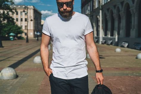 Вид спереди Молодой бородатый тысячелетний человек одетый в белых футболке и солнечных очках