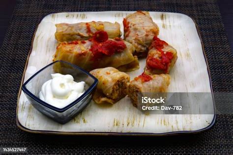 전통적인 백인 요리 톨마 또는 돌마 고기와 쌀이 든 박제 양배추 잎과 같은 접시에 사워 크림이 든 작은 유리 용기 클로즈업 0