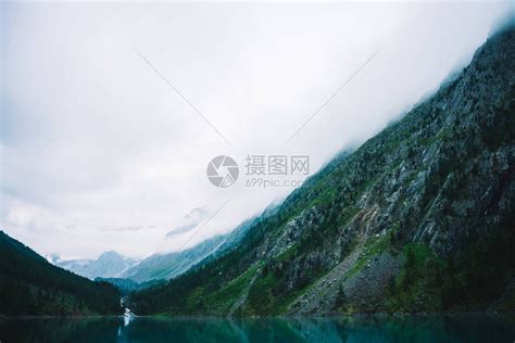 清晨山湖附近的幽灵森林山溪流入湖中在光滑的水面上荡漾低云黑暗平静的大气朦胧的林地景观高清图片下载 正版图片507469990 摄图网