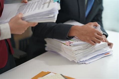 사무실 비즈니스 재무 및 회계 개념에서 문서 더미를 다루는 두 명의 회계사 사업가가 과부하 된 문서를 집어 듭니다 사무실에서 문서를 정리하고 분류하십시오 2명에 대한 스톡