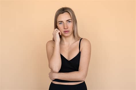 베이지색 배경 위에 서 있는 관계의 개인적인 문제에 대해 생각하는 슬픈 젊은 여성의 초상화 생각에 빠진 화가 난 소녀 외로움을 느낀다 우울하다 숙고 또는 애도 30 34세에