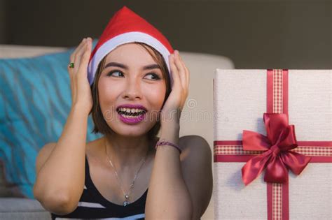 Young Beautiful And Happy Girl In Santa Hat Holding Christmas Present