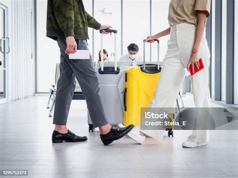 공항 터미널에서 코로나 바이러스 발병을 방지하기 위한 발로 얼굴 마스크 인사를 하는 아시아 젊은 관광객 서로 멀리 앉아 있는 사람들 빈 의자 좌석에 적십자 쇼 사회적 불변