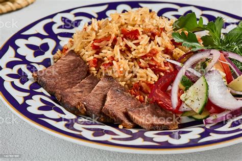 전통적인 우즈벡 음식 쇠고기와 함께 Plov 동양 요리 쌀 고기 및 향신료가있는 필라프 전통적인 우즈벡 접시에 쇠고기를 곁들인 플로브 필라프와 동양 세라믹 플레이트의 구성