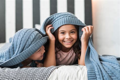 Gl Cklicher Junge Der Seine Schwester Liegt Unter Der Decke Auf Bett Betrachtet Kostenlose Foto