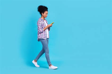 예쁜 쾌활한 소녀의 전체 길이 사진 입고 체크 무늬 셔츠 타이핑 애플 삼성 아이폰 빈 공간 격리 된 푸른 색 배경 걷기에 대한 스톡 사진 및 기타 이미지 Istock