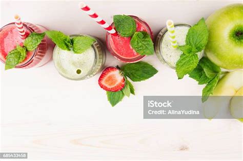 장식 프레임 녹색과 빨간색 과일 스무디 딸기와 사과 평면도의 밀 짚 민트 잎 유리 항아리에 화이트 나무 보드 배경 공간을 복사