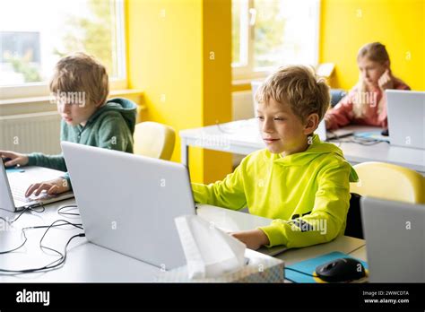 Blond Boys Using Laptops Learning Computer Coding In Classroom Stock