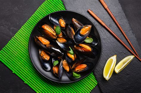 해산물 홍합 바질 잎은 녹색 대나무 매트와 돌 테이블에 레몬과 젓가락과 검은 접시에 바질 잎 고급 요리에 대한 스톡 사진 및 기타 이미지 Istock