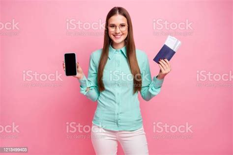 긍정적 인 쾌활한 소녀 관광 홀드 스마트 폰 사용 예약 주말 티켓 여권 착용 스타일 세련된 트렌디 한 청록색 셔츠 흰색 바지 바지 고립 파스텔 색상 배경 갈색 머리에 대한