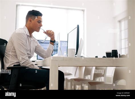Software Developer Sitting At His Office Desk Looking At Laptop