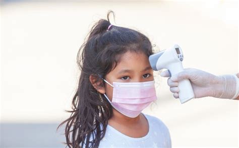 Premium Photo Cropped Hand Checking Temperature Of Cute Girl Outdoors