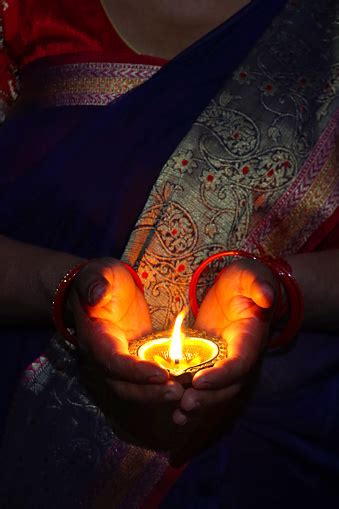 손손바닥에 불이 붙은 기름이 가득한 점토 디야를 들고 있는 인식할 수 없는 사람의 이미지 불이 켜진 심지의 디왈리 오일 램프 어두운 디왈리 축하의 깜박이는 불꽃 전경에