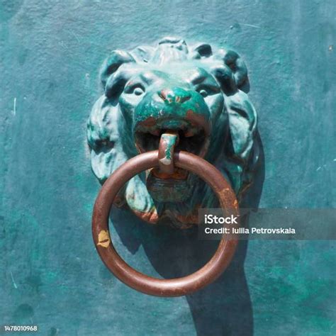 문 두드리는 사람은 집 현관문에 고정되어 있습니다 그것은 금속으로 만들어졌으며 벽에 고정 된 문 두드리는 사람의 금속 부분을 두드리는 링 형태입니다 사자의 총구 Val Di