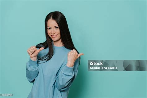 캐주얼에 쾌활한 갈색 머리 젊은 여자 광범위하게 미소 청록색 스튜디오 배경을 통해 여유 공간에서 옆으로 포인트 프로모션 및 할인 컨셉 T 셔츠에 대한 스톡 사진 및 기타