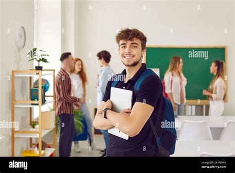 Portrait Of Student With Backpack And Tablet Computer Against Background Of Class With His