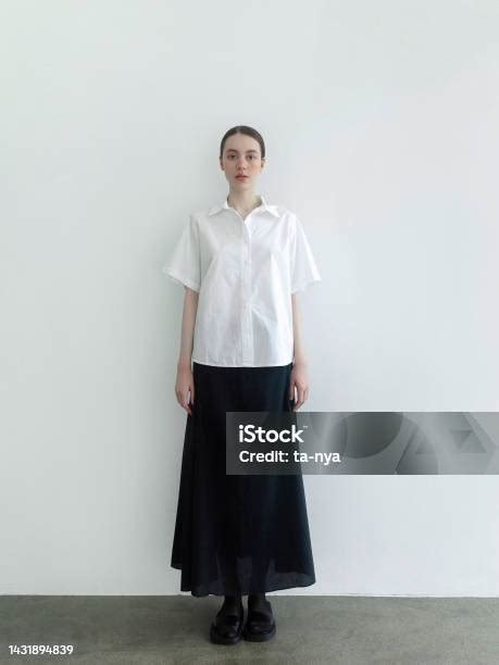 세련 된 미니멀리즘 옷을 입고 아름 다운 젊은 여자 스칸디나비아 스타일 화이트 반 소매 셔츠 긴 넓은 검은 맥시 스커트 패션 모델 포즈를 취하는 표현 자신감 있는 예쁜 패션