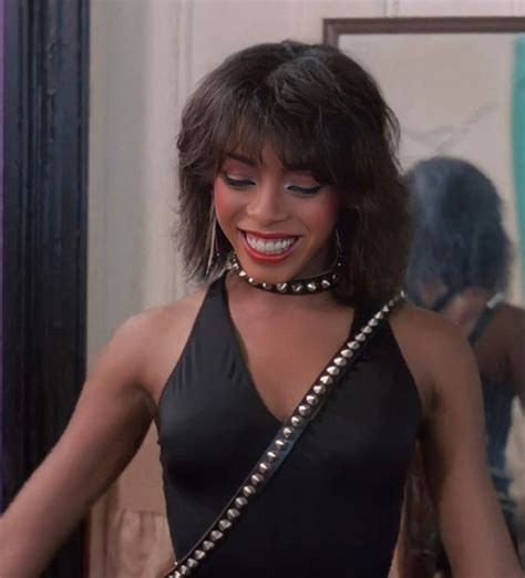 A Woman In A Black Dress Is Smiling And Holding Onto A Chain Around Her