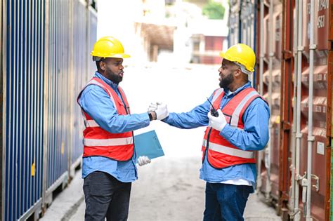 노란색 안전모와 안전 조끼를 입은 두 명의 엔지니어 또는 감독 컨테이너 화물의 전문가로 수입 수출을 위해 화물 화물선에서 선적하기 위해 컨테이너에 재고를 확인합니다 물류