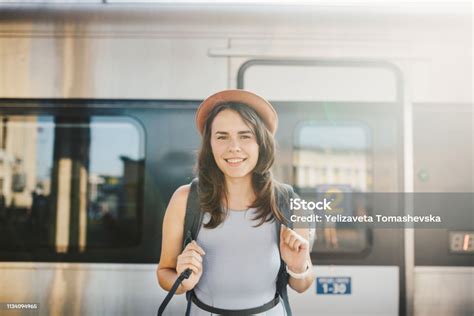 테마 철도 및 여행 여름에 드레스와 모자에 관광 고립 된 매트에 대 한 배낭 및 장비와 기차 역 기차 배경에 서 있는 이빨을 가진 초상화 젊은 백인 여자 귀여운에 대한 스톡